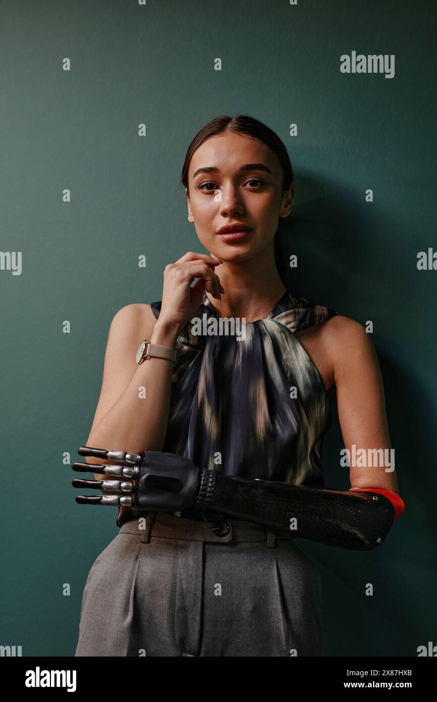 Confident woman with black bionic arm leaning on green wall Stock Photo ...