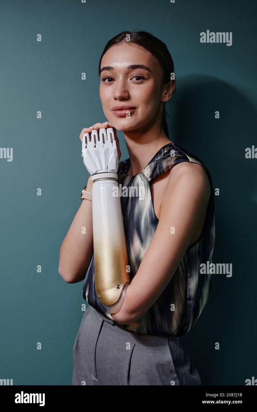 Smiling woman with bionic arm standing in front of green wall Stock ...