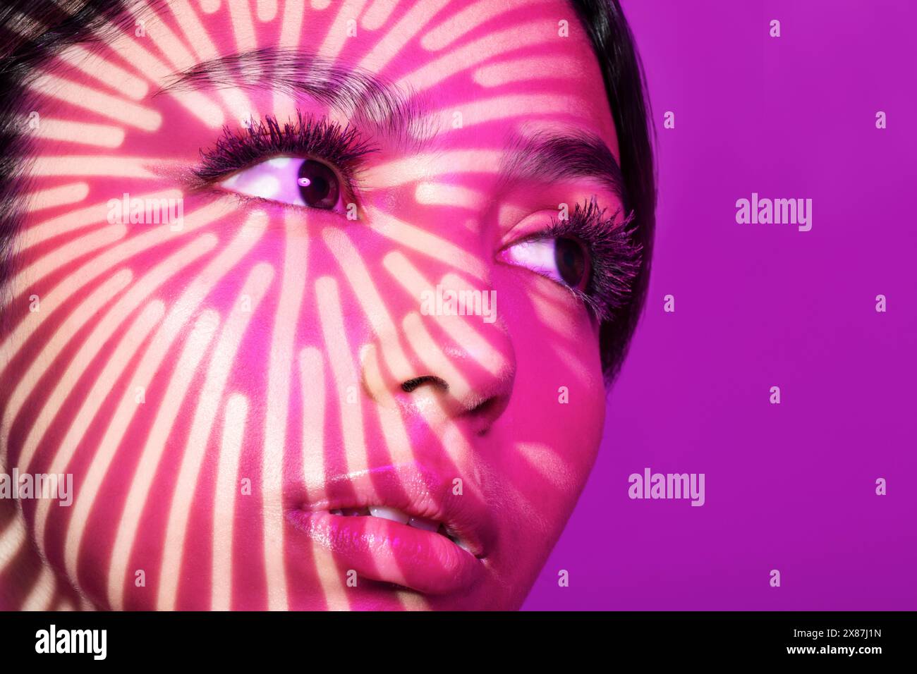 Young woman with light pattern on face against pink background Stock ...