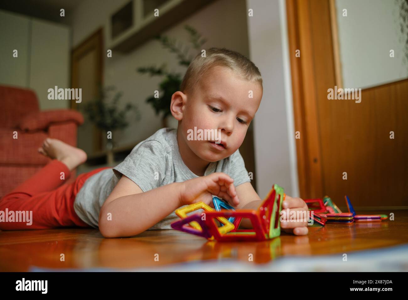 Boy lying on floor and playing with building toys at home Stock Photo ...