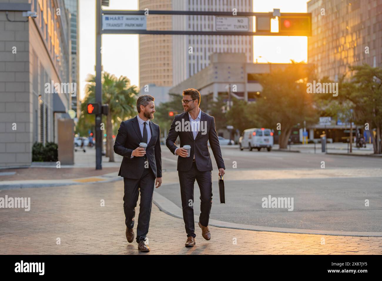 Photo of businessmen in suits walking outdoor through city street. Two ...