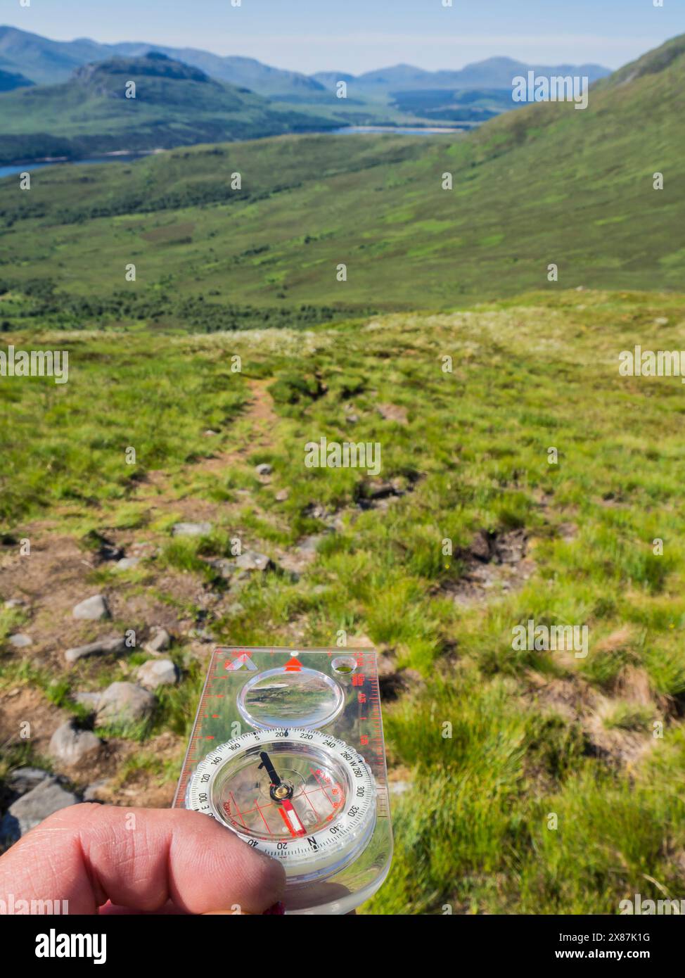 UK, Scotland, Hand of male hiker using navigational compass in ...