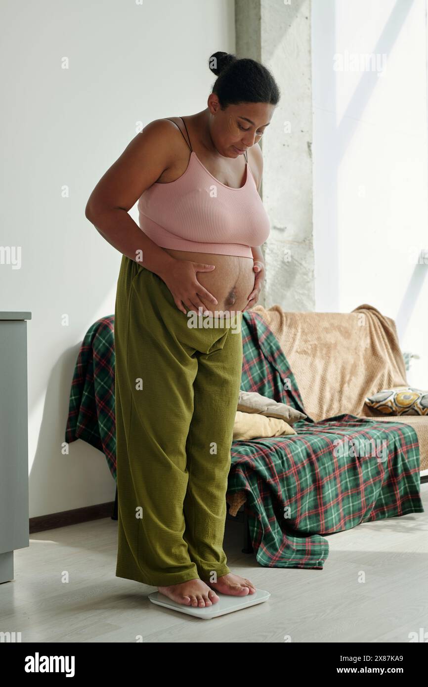 Plus size pregnant woman standing on scale at home Stock Photo - Alamy
