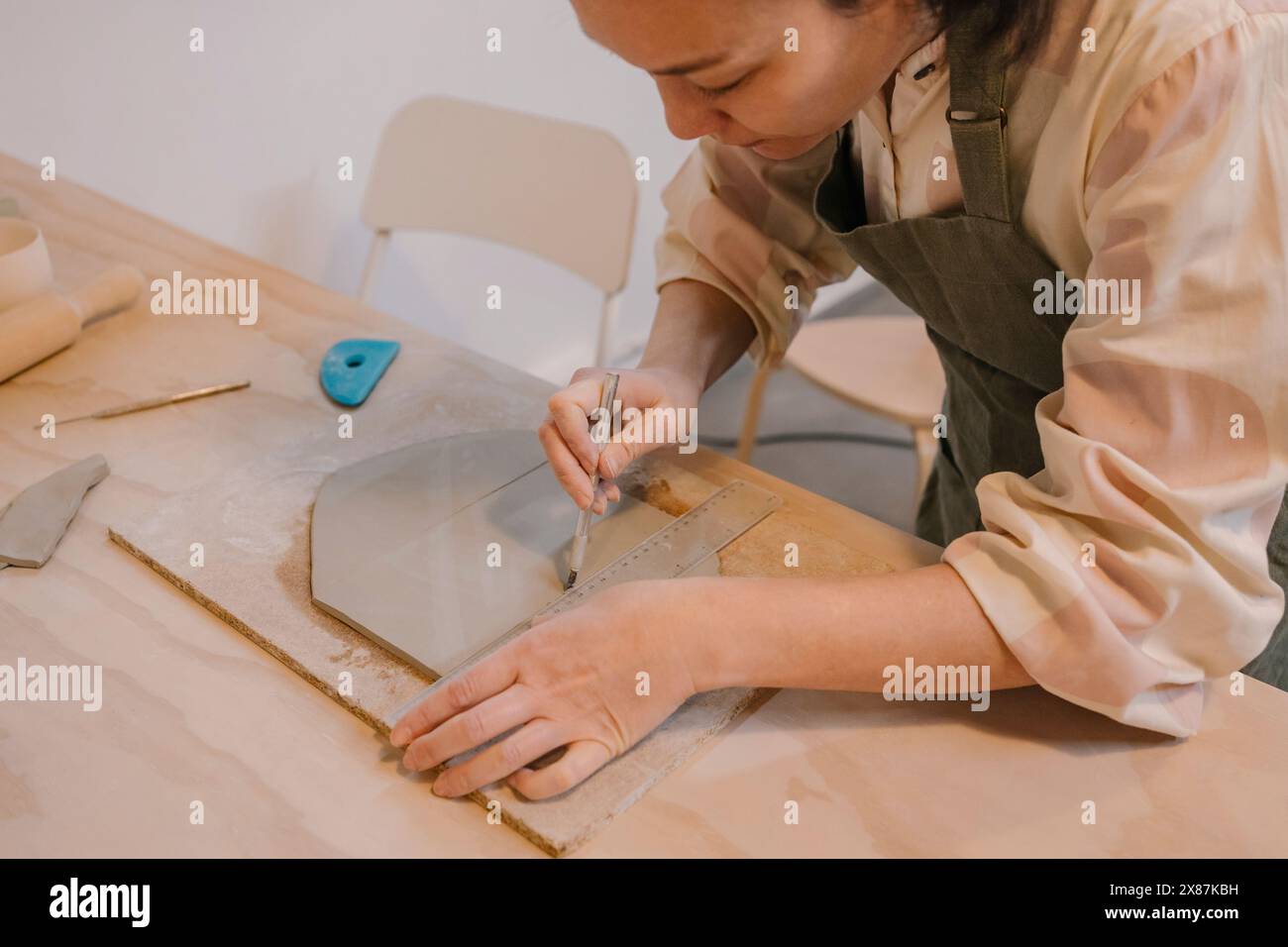 Skilled craftsperson cutting clay on table at pottery workplace Stock ...