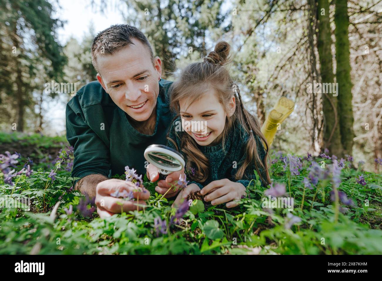 Happy girl and father looking at flowers with magnifying glass in ...