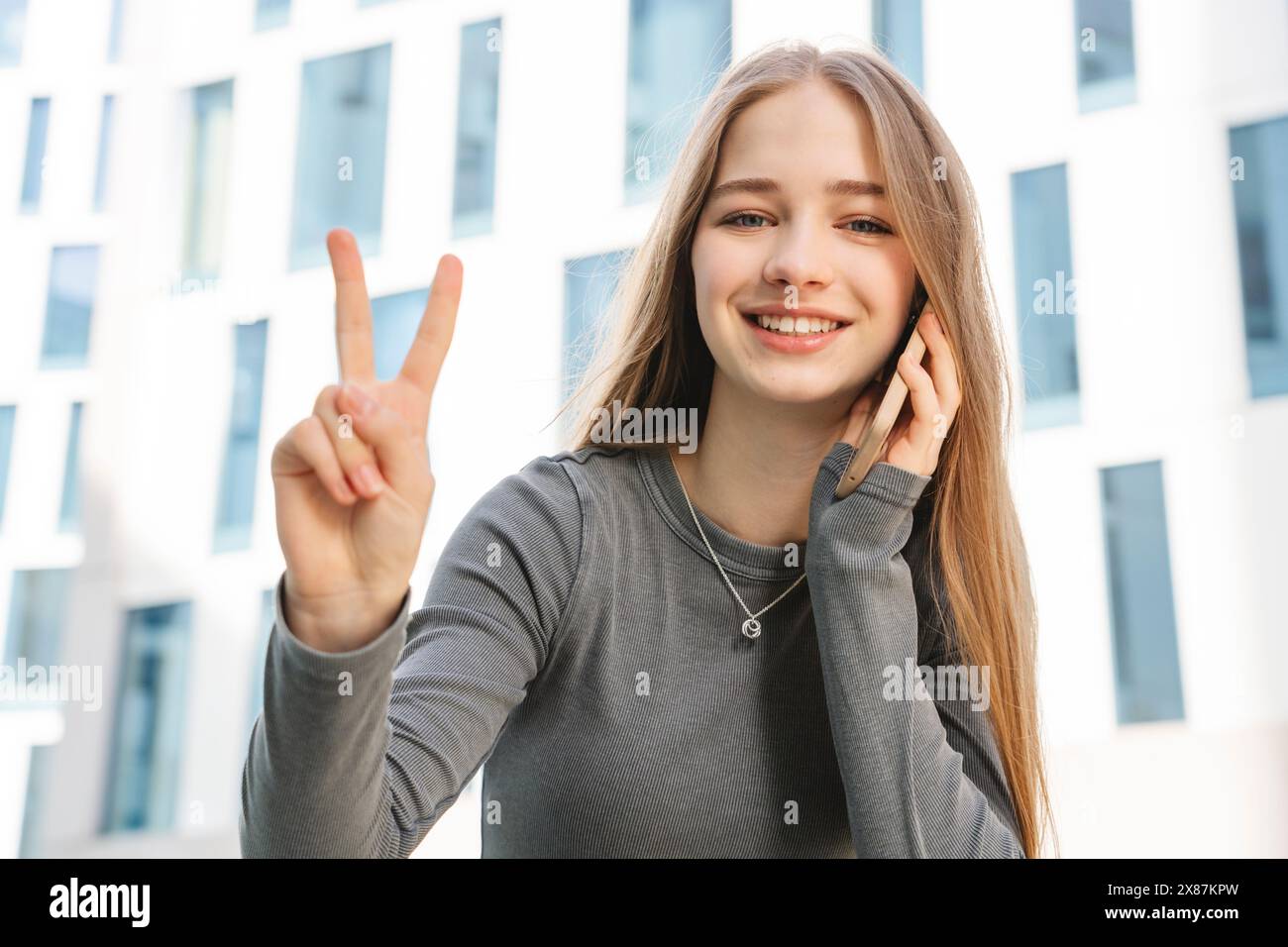 Smiling teenage girl talking on mobile phone showing peace sign Stock ...