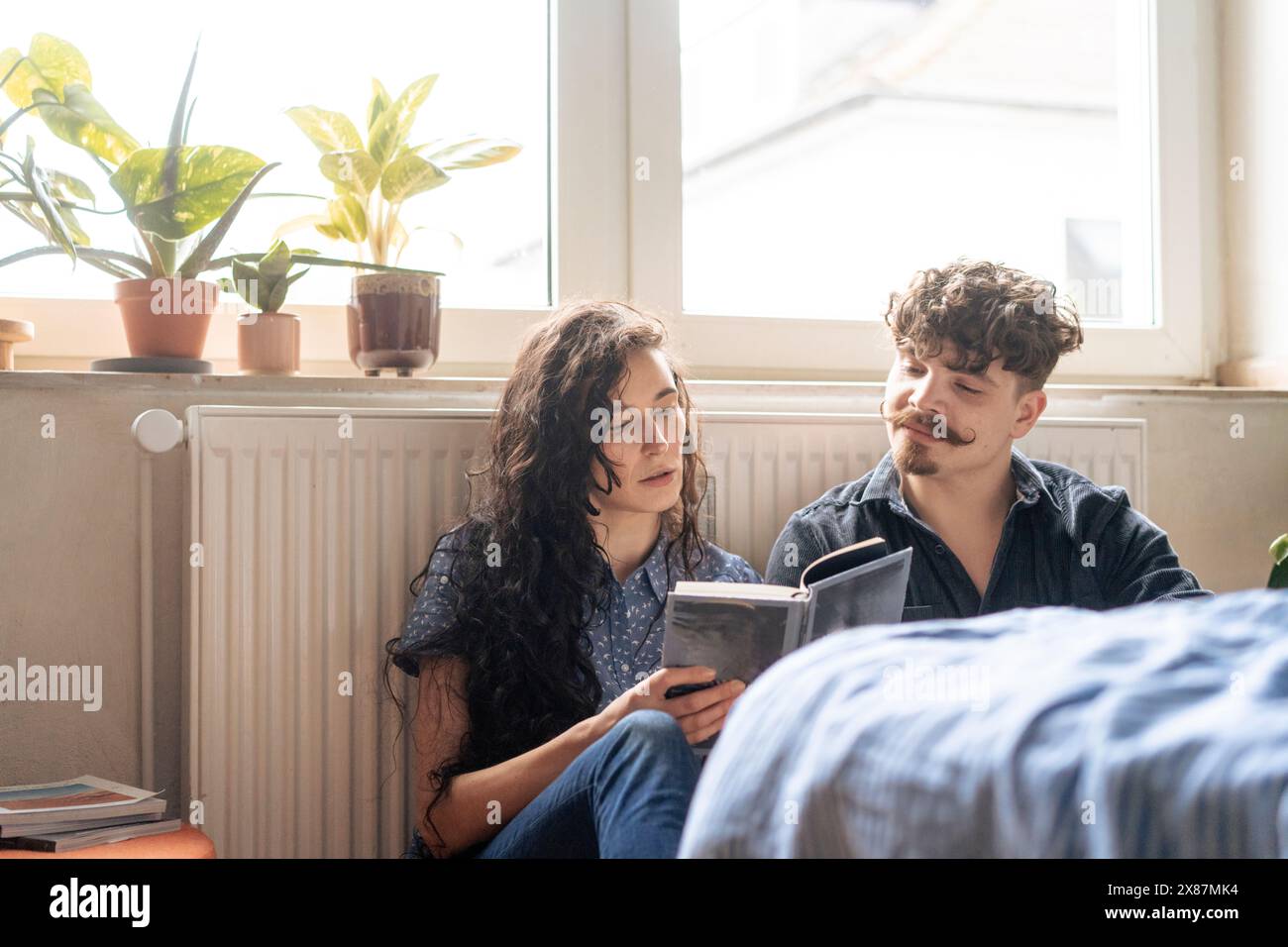 Boyfriend and girlfriend reading book at home Stock Photo - Alamy