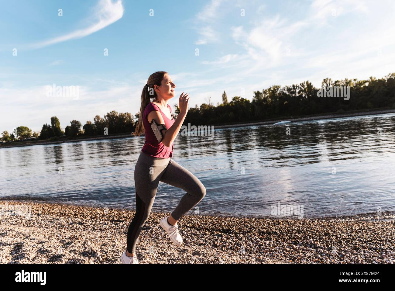 Woman running in front of river under cloudy sky Stock Photo - Alamy