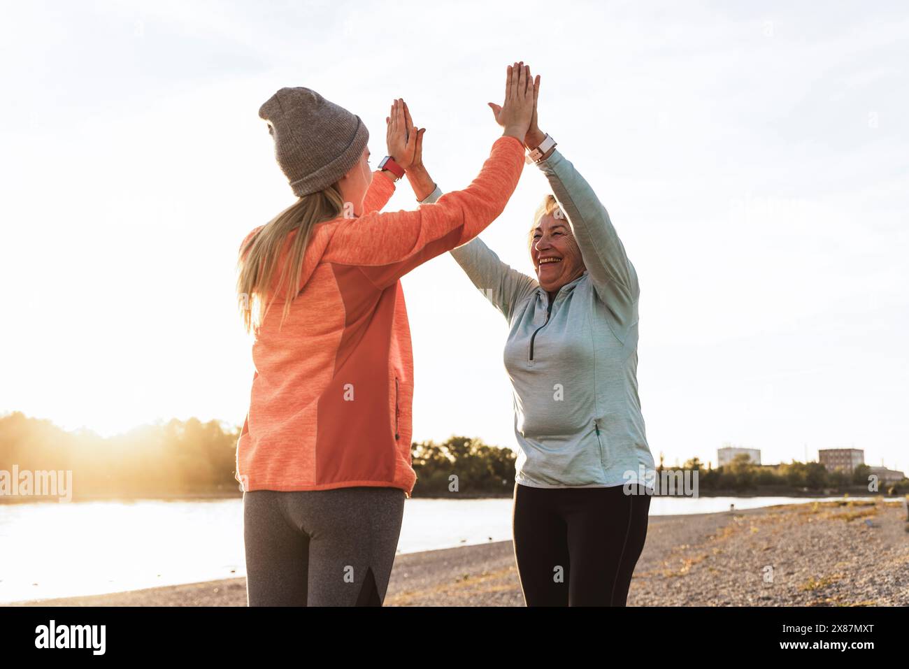 Happy woman giving high-five to grandmother near river on sunny day ...