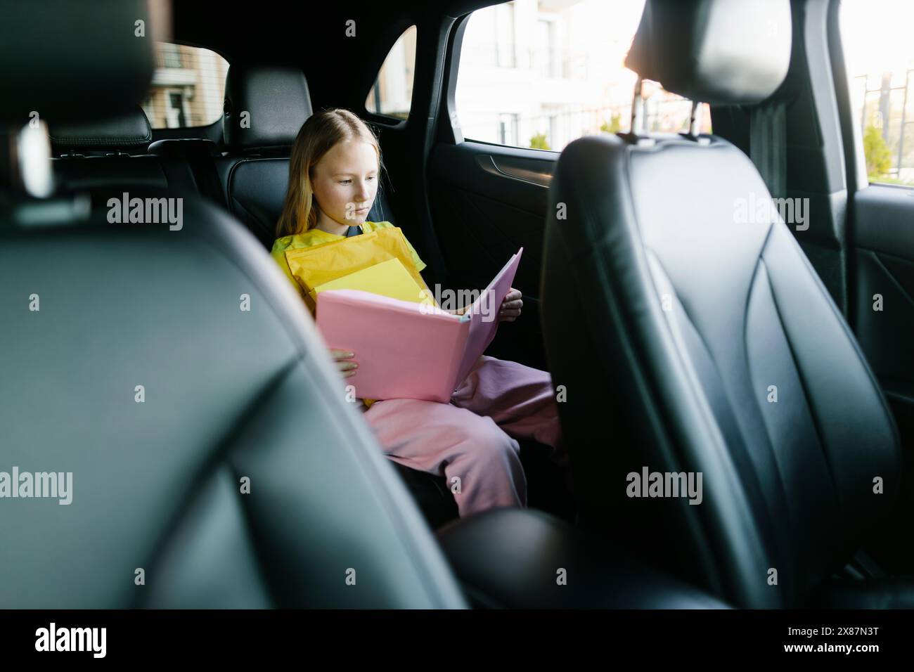 Focused girl reading book in backseat of car Stock Photo - Alamy
