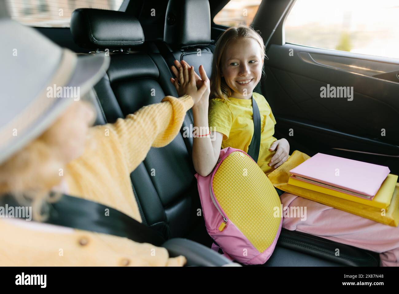 Happy sisters giving high-five sitting in backseat of car Stock Photo ...