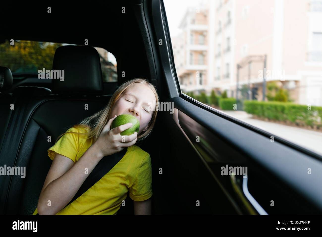 Girl eating apple and leaning on car window Stock Photo - Alamy