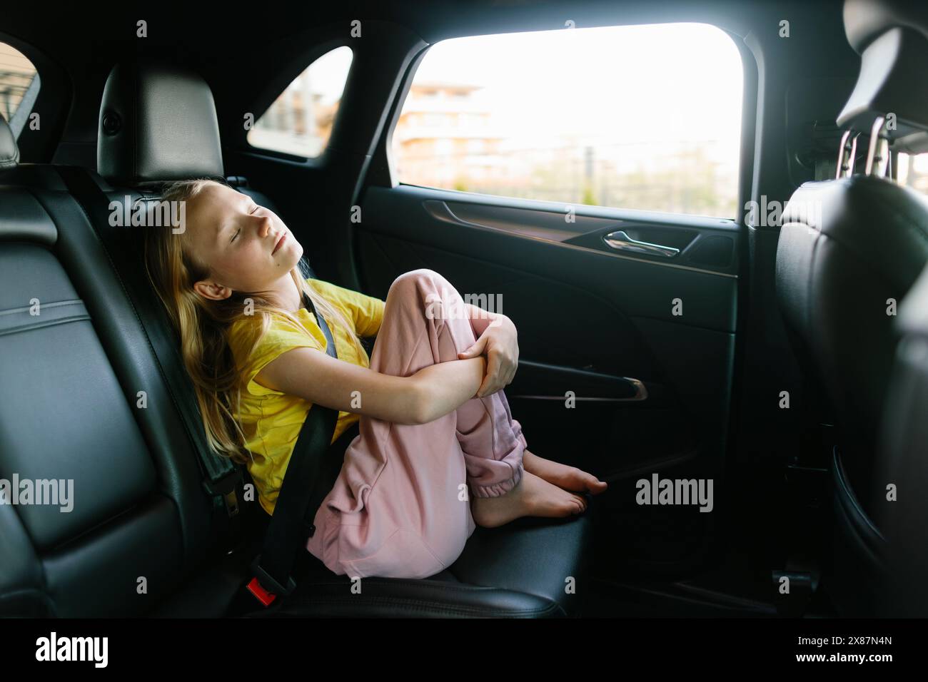 Girl hugging knees and sleeping in car Stock Photo - Alamy