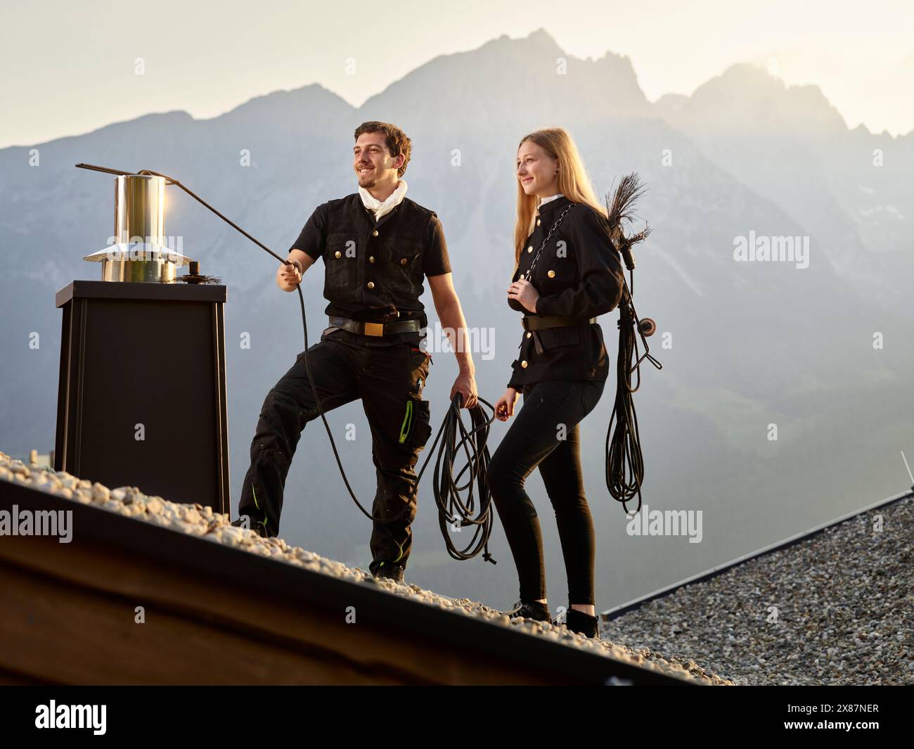 Smiling chimney sweeper with teenage trainee standing on rooftop Stock ...