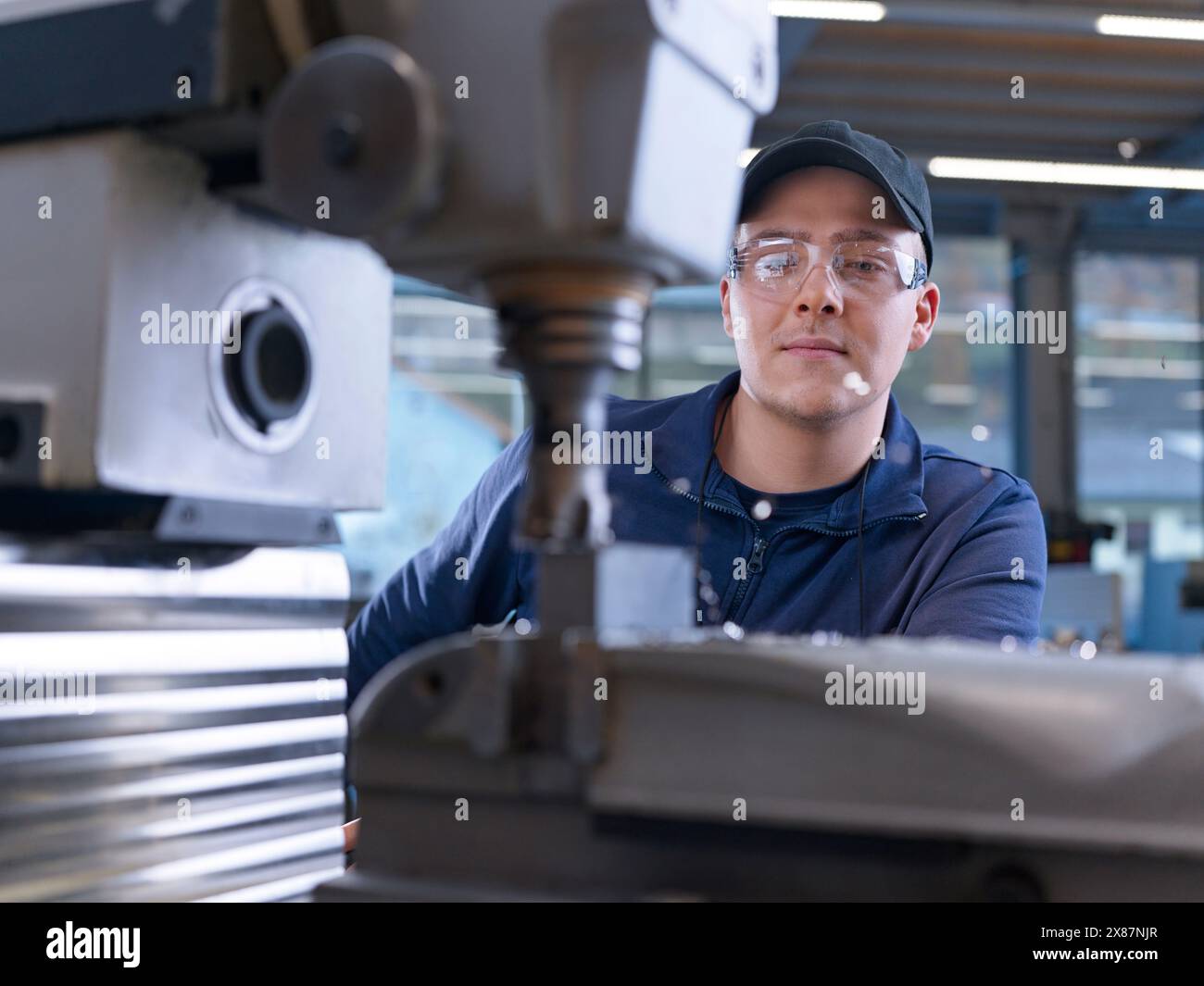 Engineer wearing cap working with CNC machine at factory Stock Photo ...