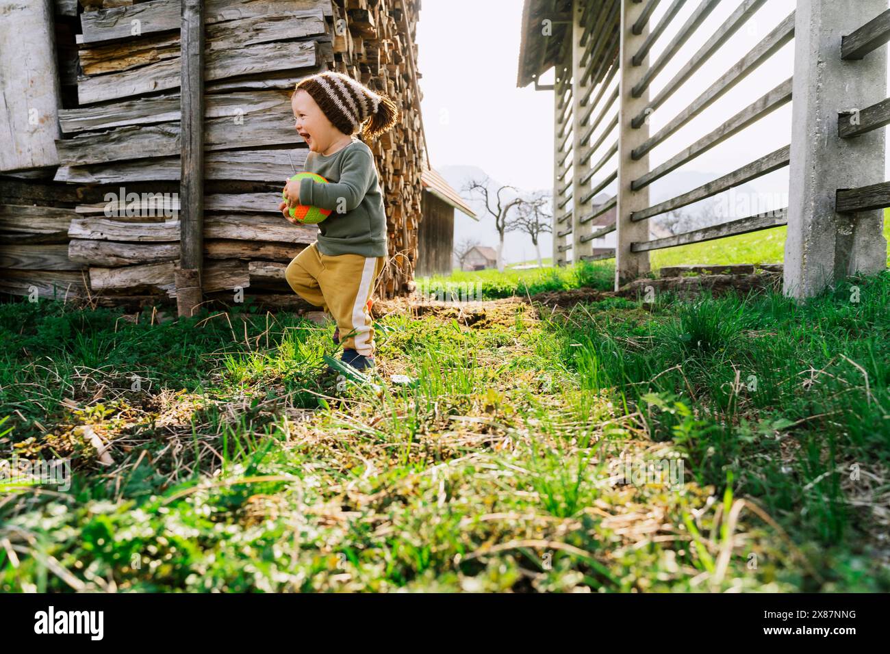 Cheerful boy running with ball by house Stock Photo - Alamy