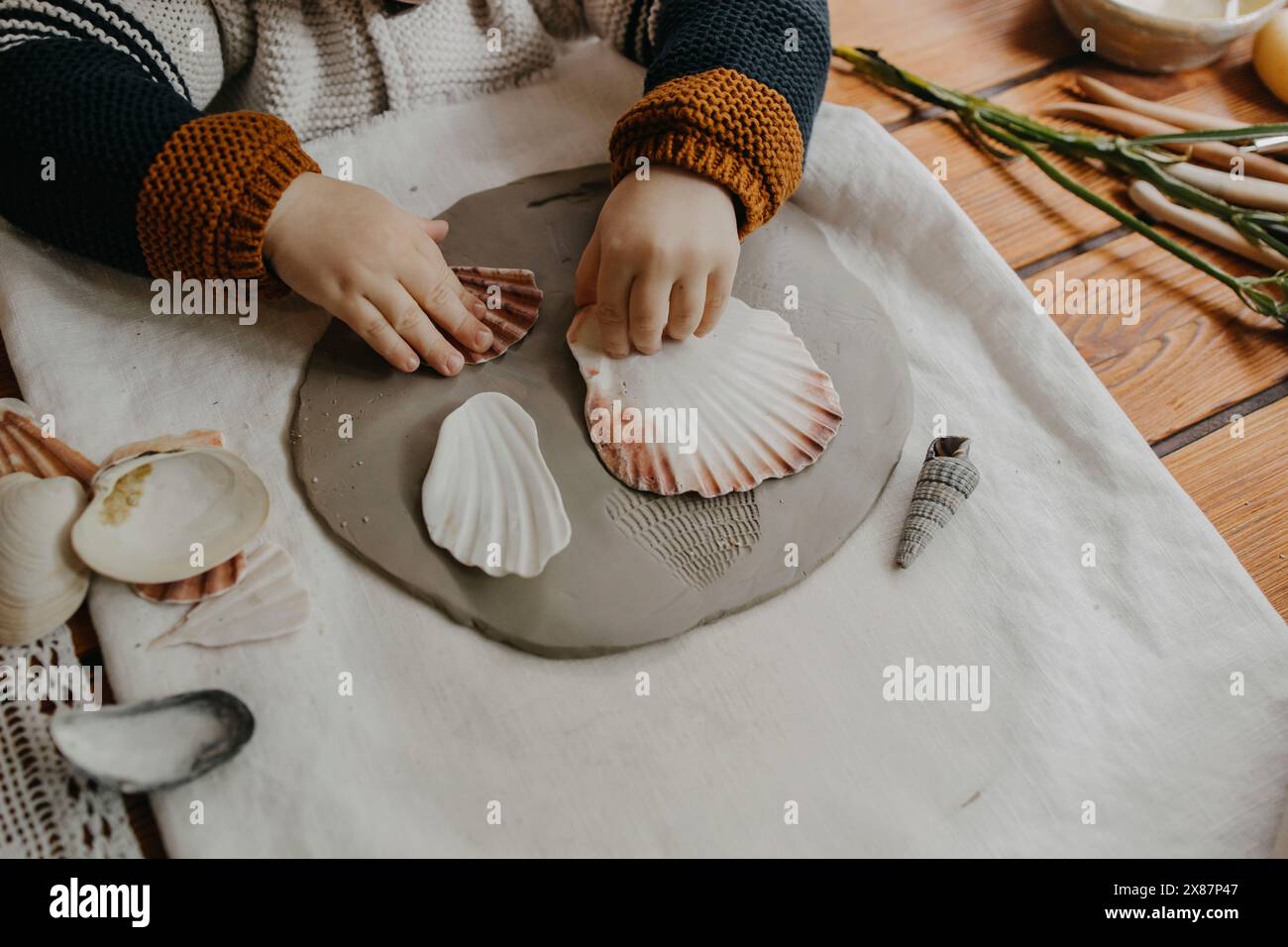 Boy making seashell imprint on clay at home Stock Photo - Alamy