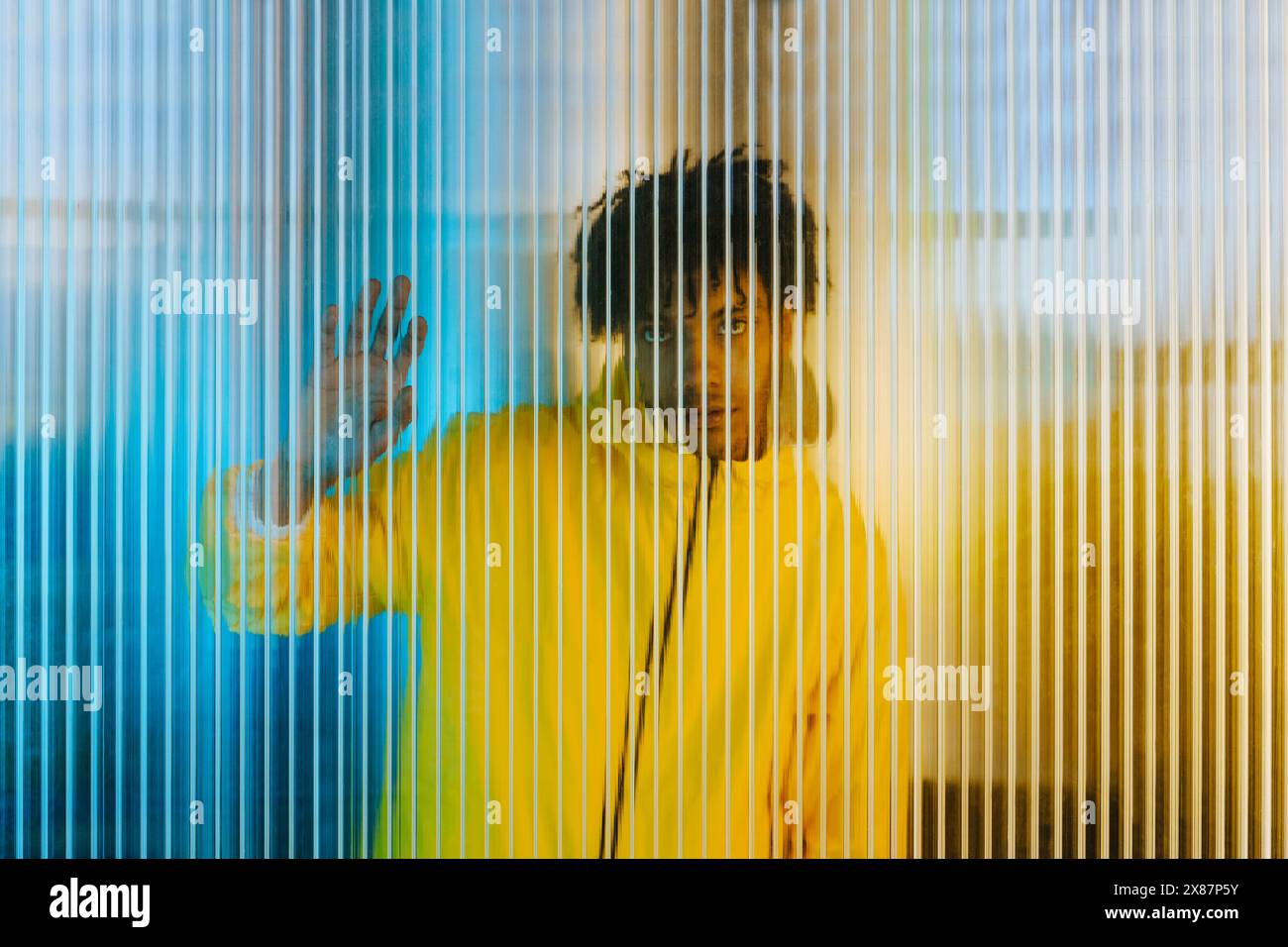 Young man standing behind striped wall Stock Photo - Alamy