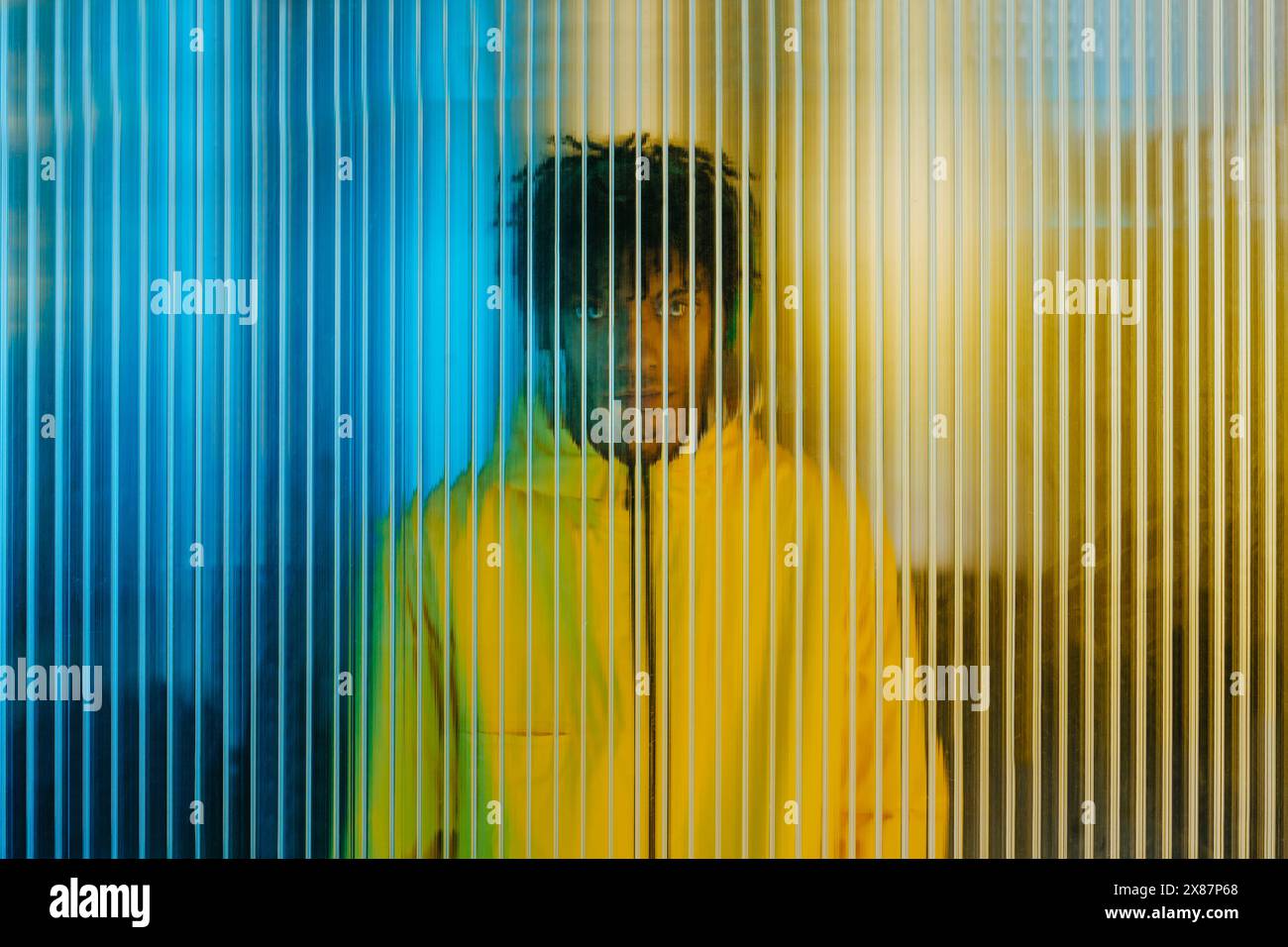Serious young man behind striped wall Stock Photo - Alamy