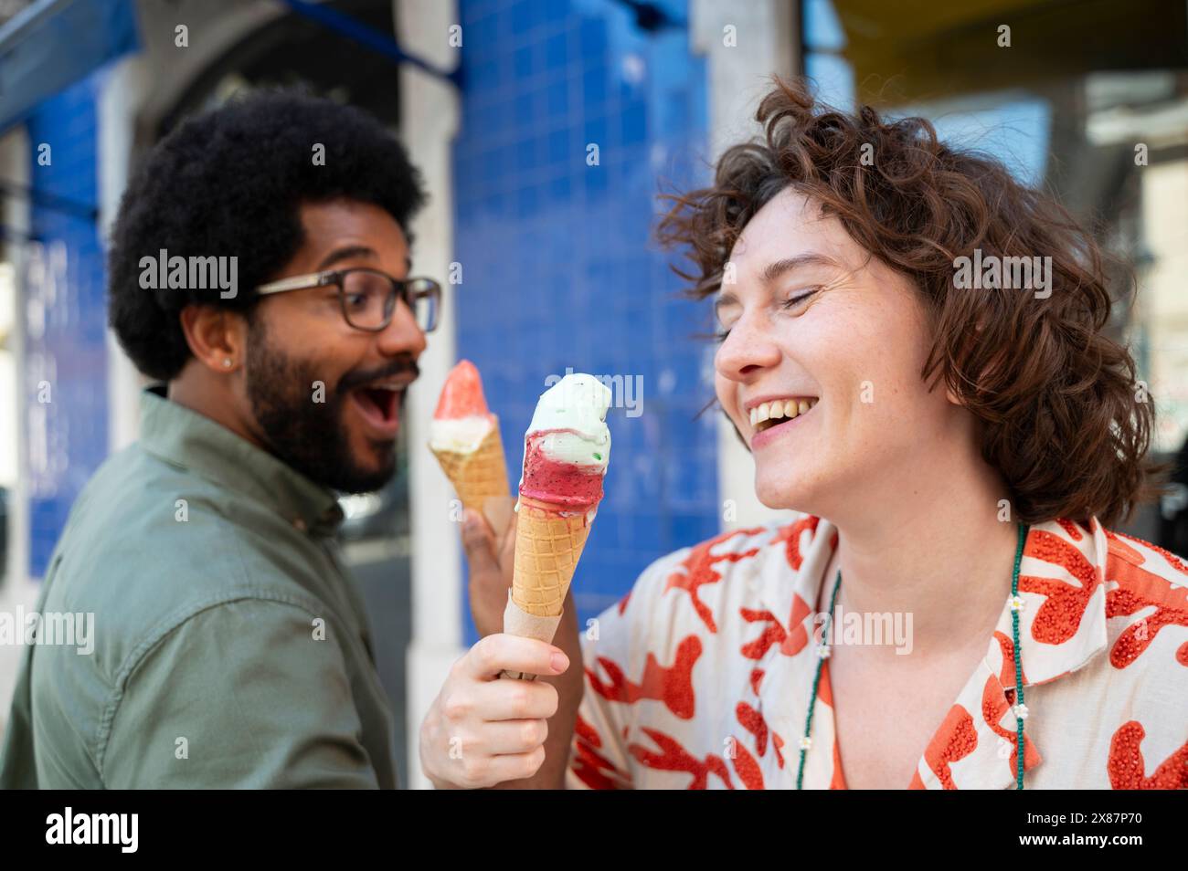 Happy couple eating ice cream cones in front of building Stock Photo ...