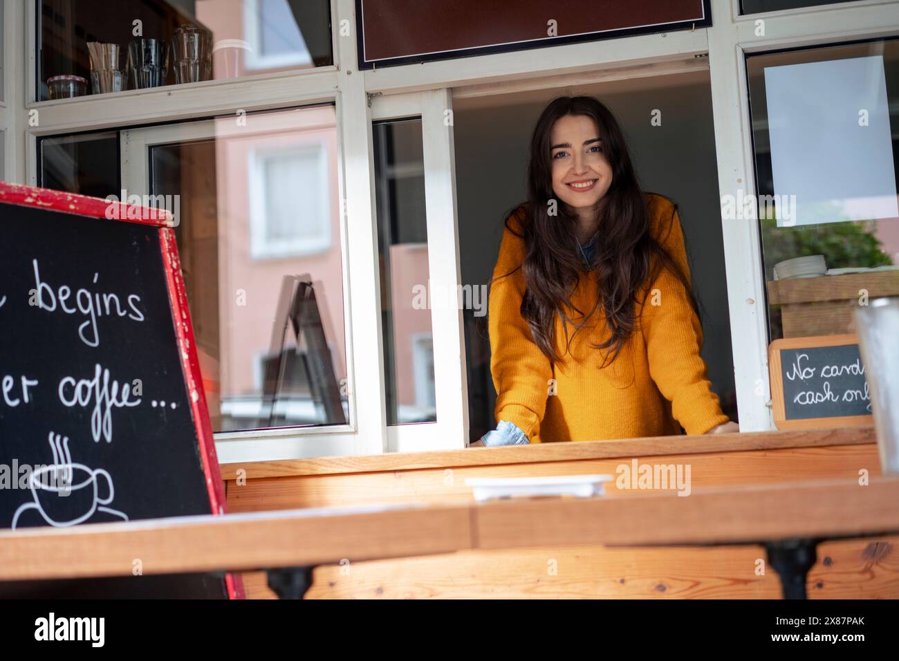 Smiling owner standing at cafe window Stock Photo - Alamy