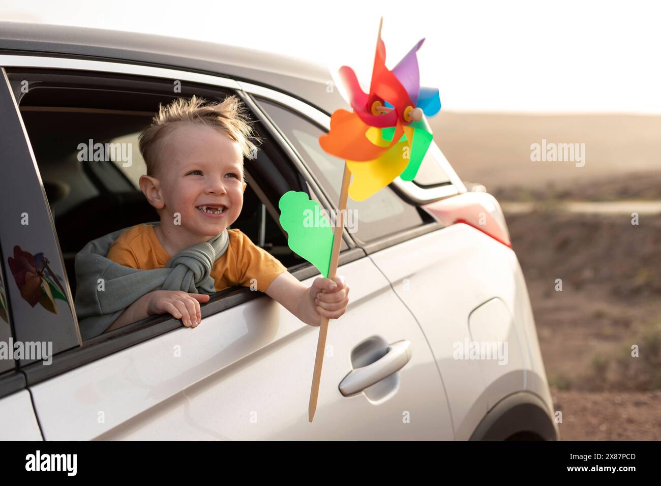 Cheerful boy holding pinwheel toy near car window Stock Photo - Alamy