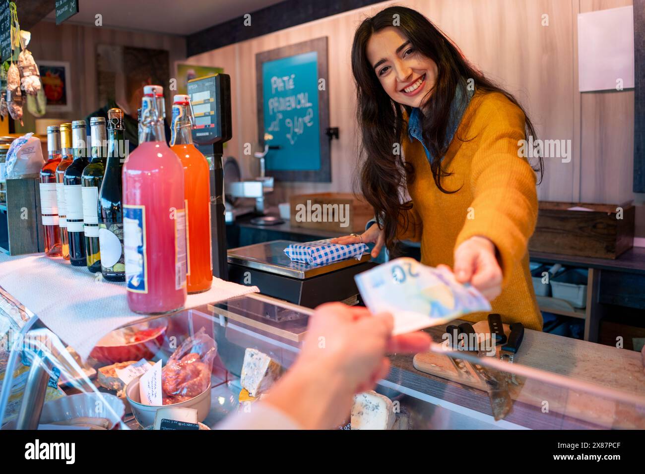 Smiling owner giving change to customer at store Stock Photo - Alamy