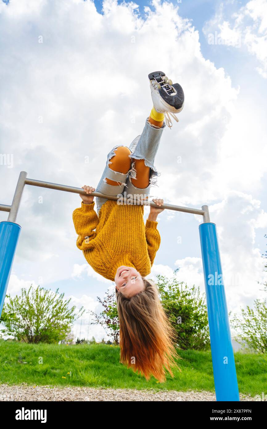 Happy girl hanging upside down on gymnastics bar at playground Stock Photo - Alamy