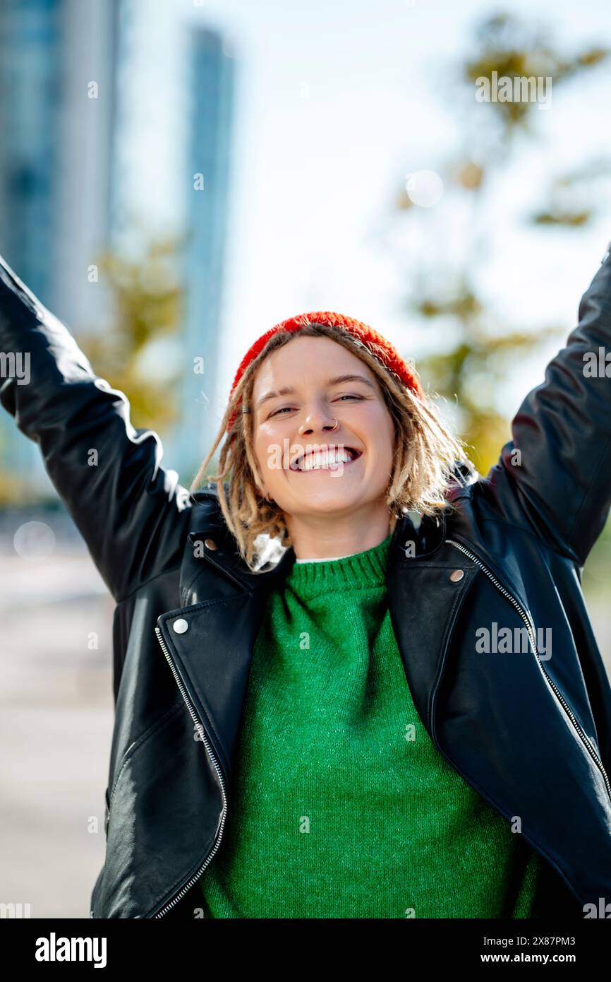 Happy young woman with arms raised wearing leather jacket Stock Photo ...