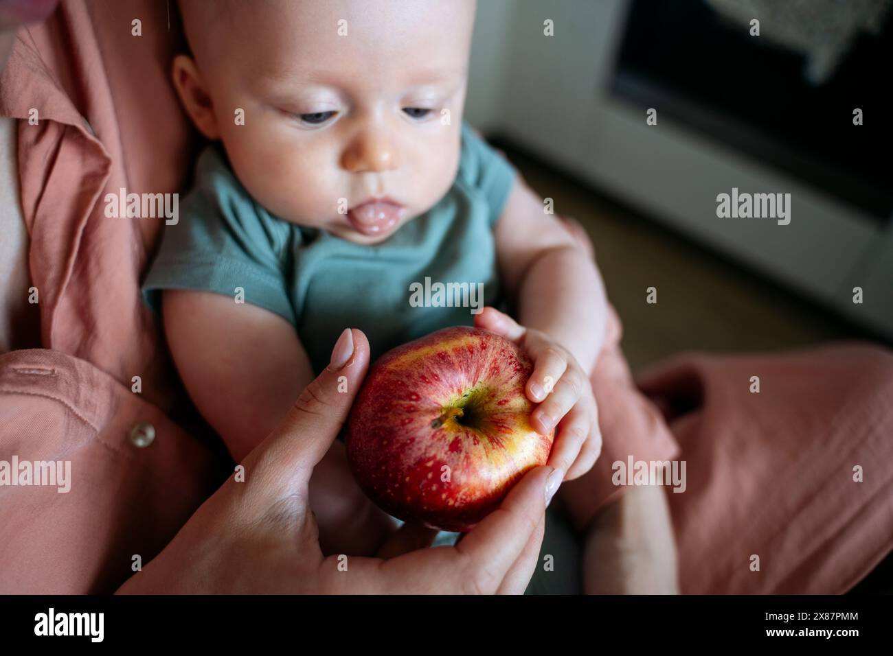 Cute baby boy and mother holding apple at home Stock Photo - Alamy
