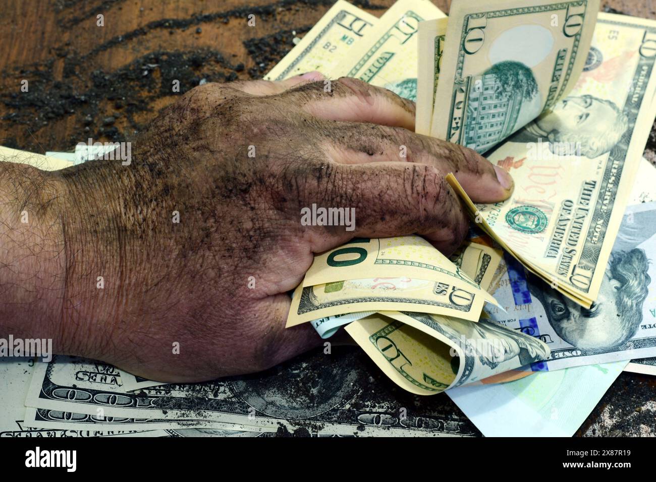 Man's hand smeared with dirt, a symbol of theft, squeezes illegally ...