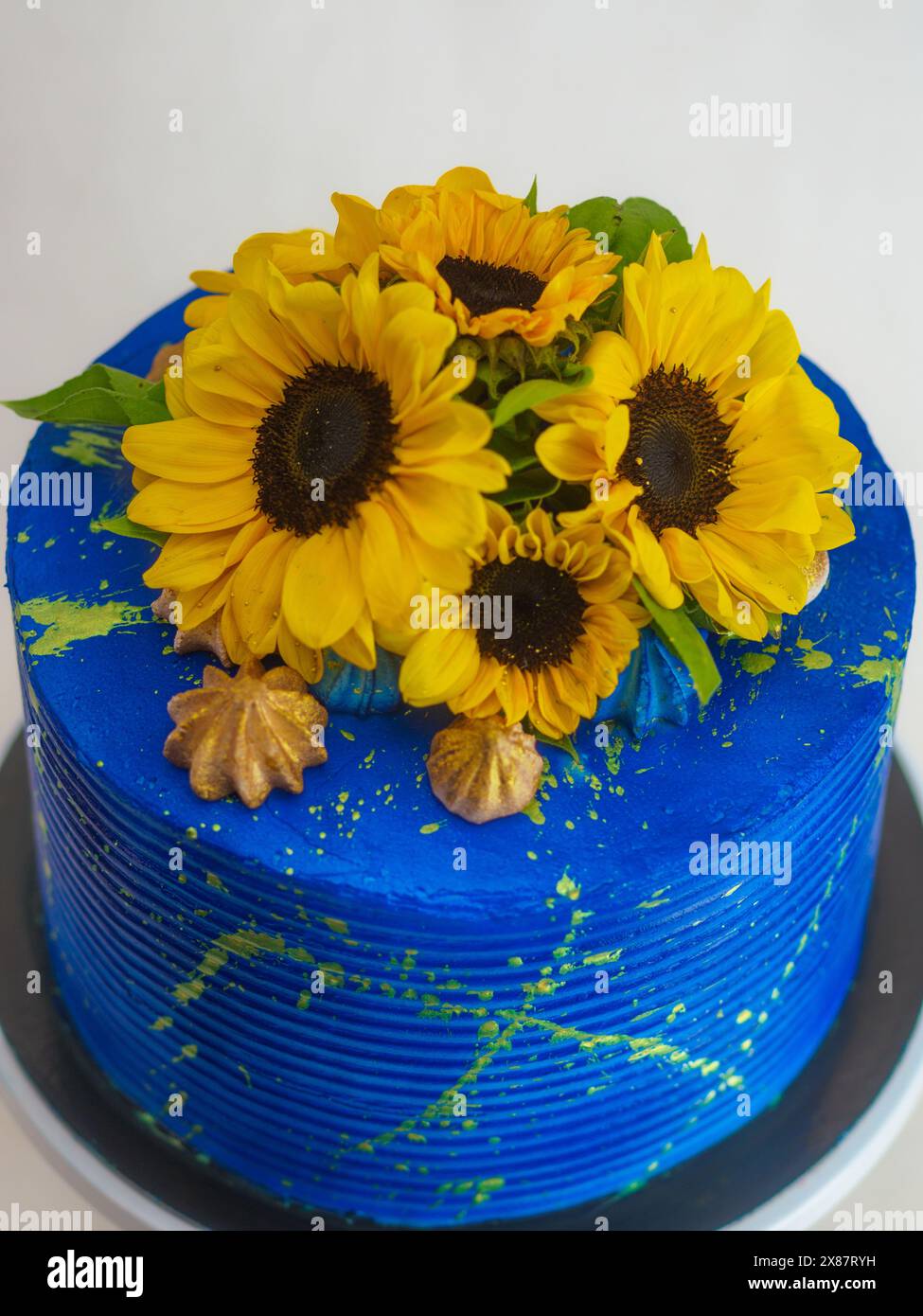 Stunning cake adorned with fresh sunflowers and vibrant blue frosting ...