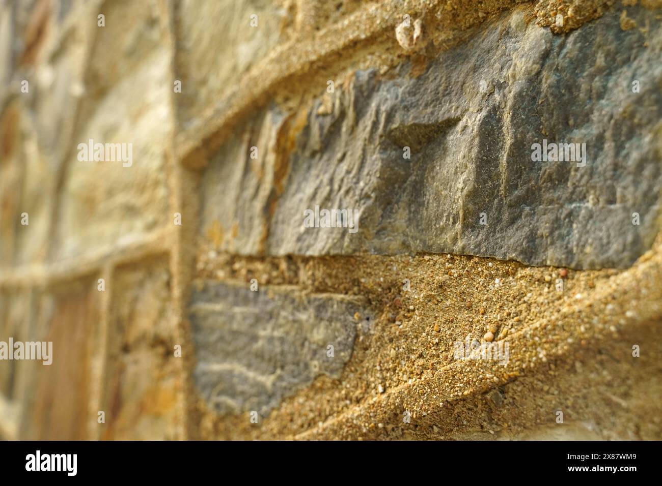 Detailed close-up view of a stone wall with sand grains layered on its ...