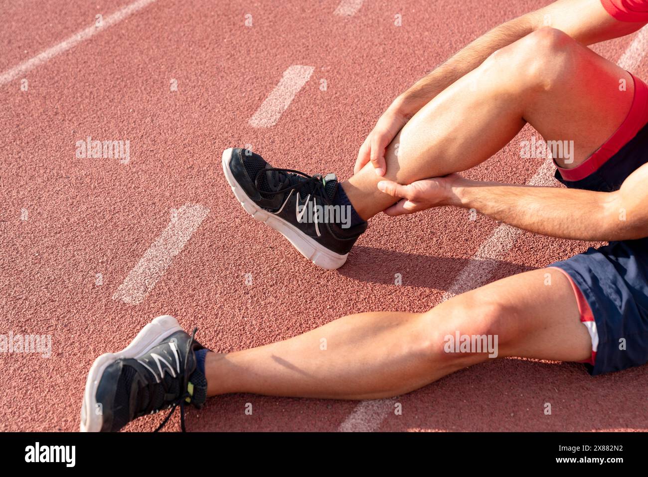 Athlete with injured ankle is holding his knee. knee and foot joint ...