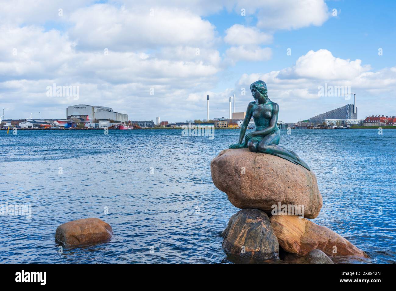 COPENHAGEN, DENMARK - APRIL 14, 2024: Bronze statue of the Little Mermaid sitting on a rock at ...