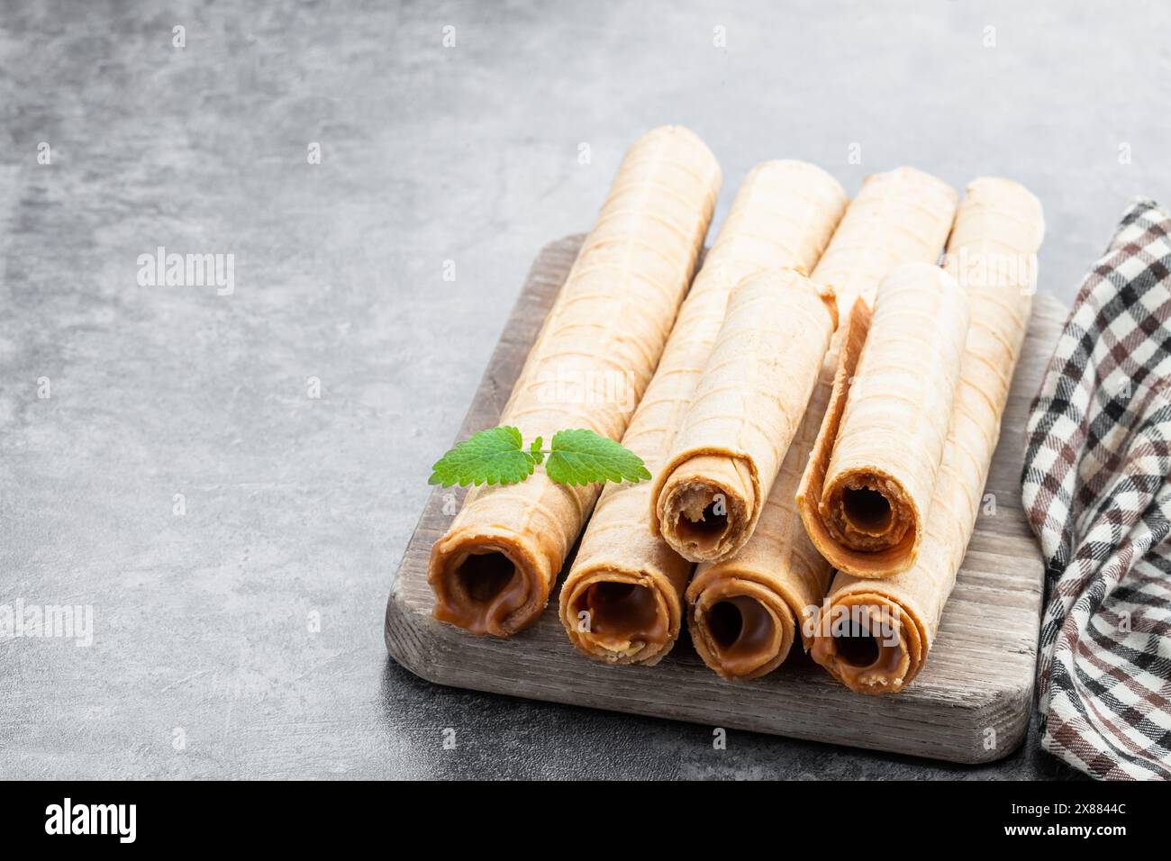 Delicious of waffer rolls with boiled condensed milk on gray background ...