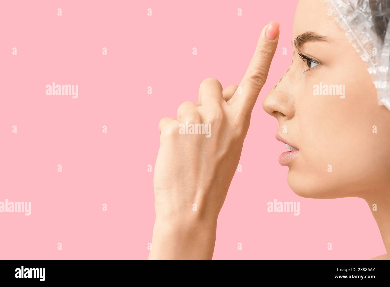 Young woman in medical hat checking her nose before plastic surgery ...