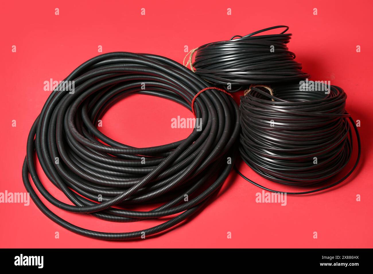 Rolled flexible conduit tube and cables on red background Stock Photo ...