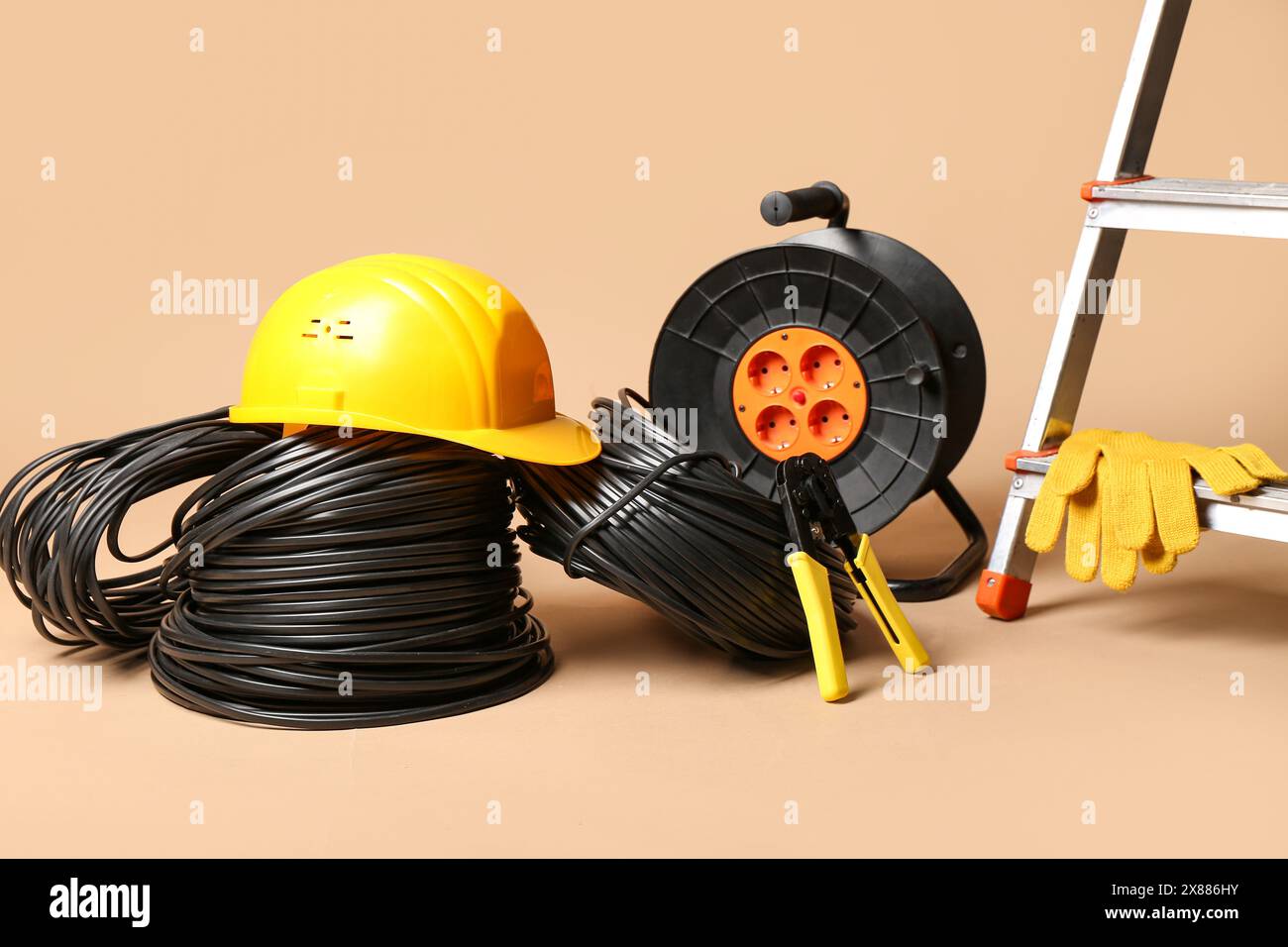 Rolled wires, crimper, hardhat and extension cable reel on beige ...
