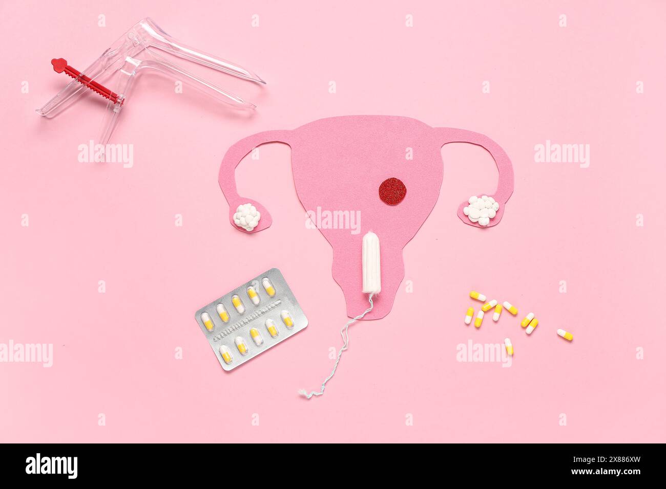 Paper uterus with gynecological speculum, tampon and pills on pink ...