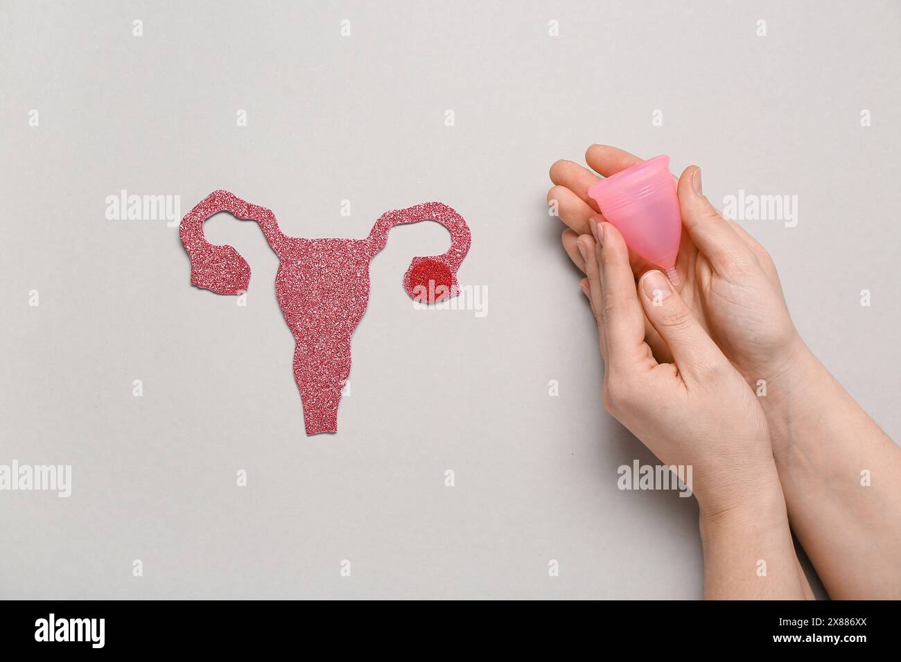 Female hands with paper uterus and menstrual cup on grey background ...