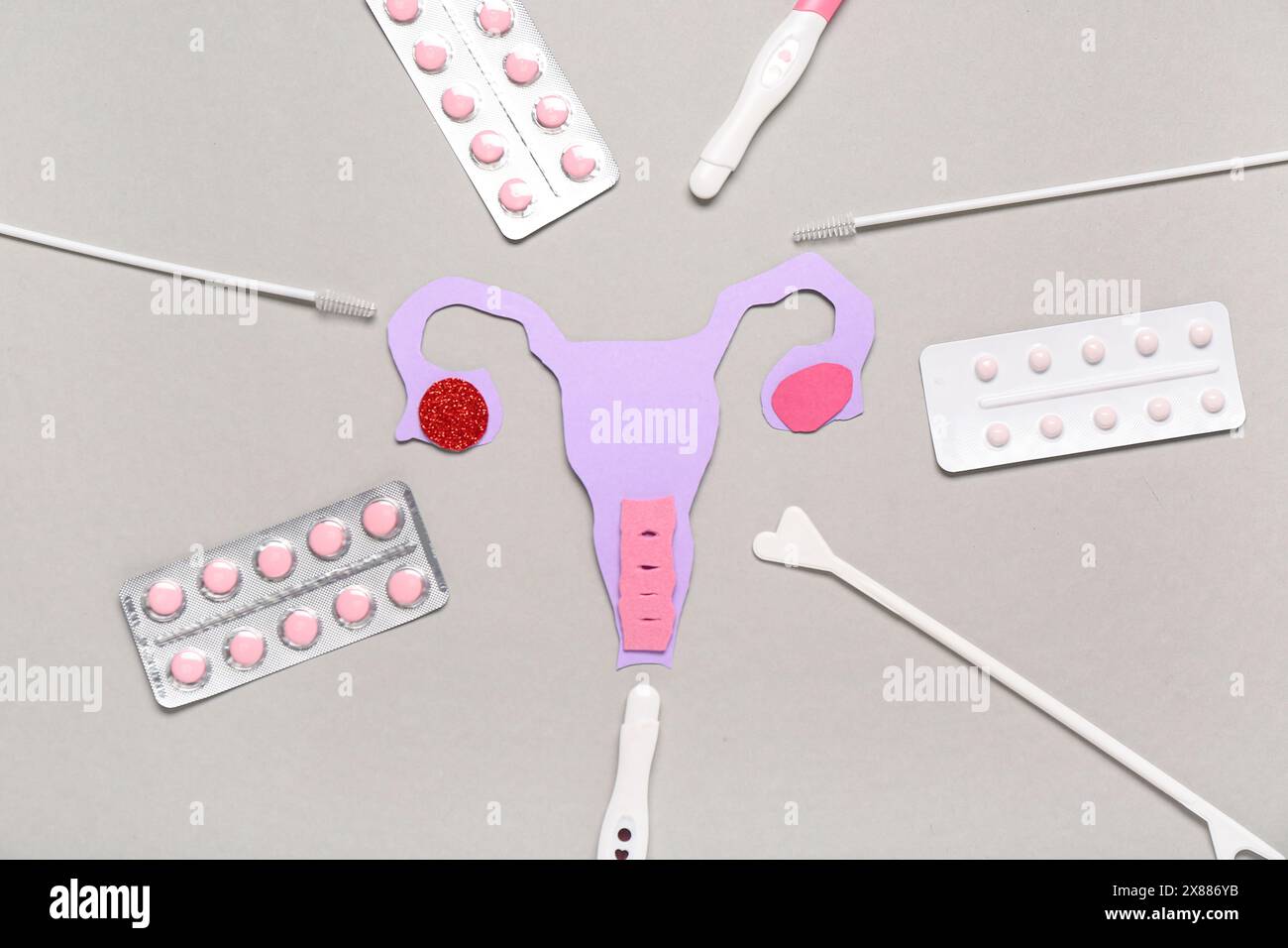 Paper uterus with pap smear test tools and pills on grey background ...