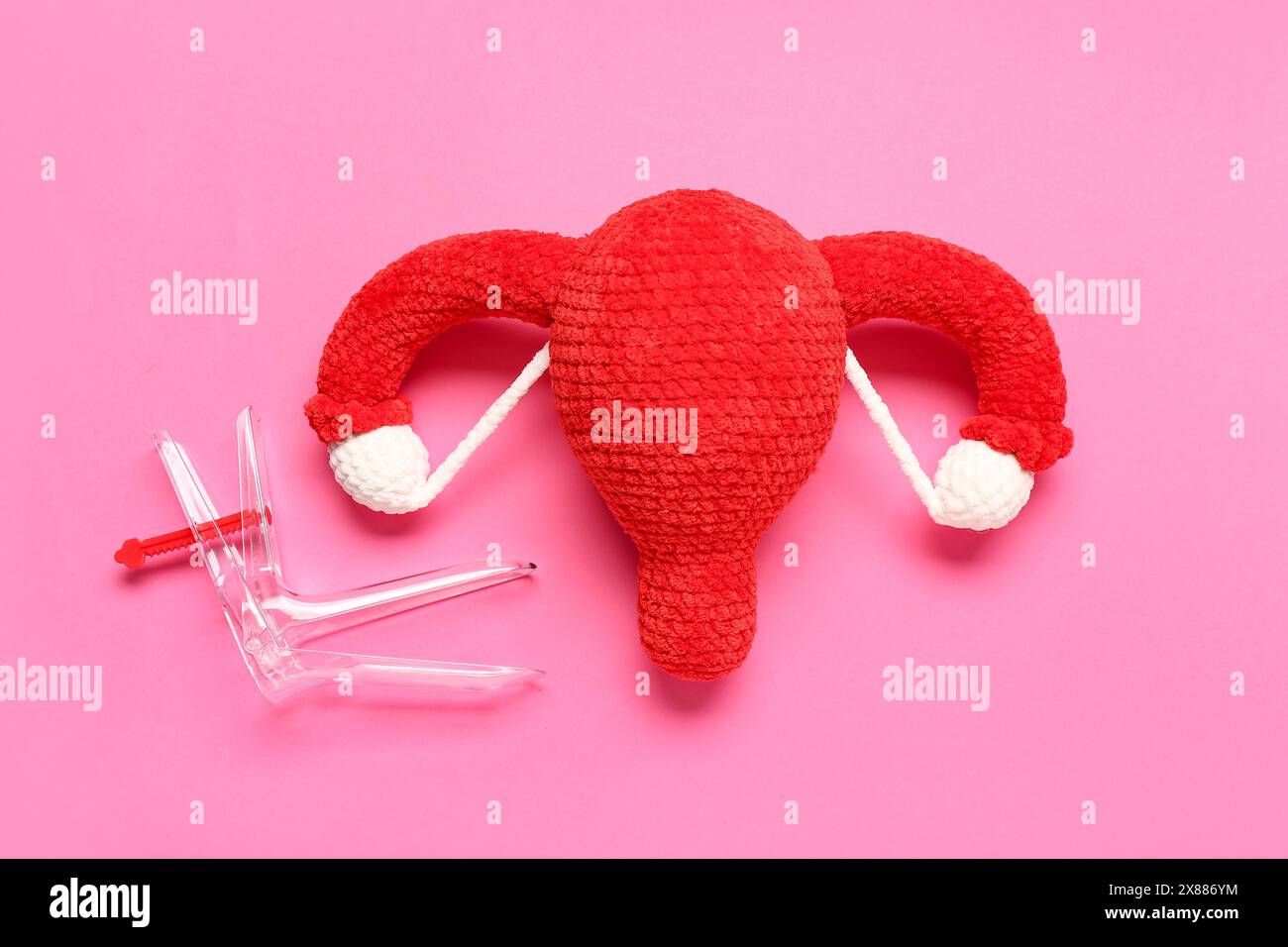 Knitted uterus and gynecological speculum on pink background Stock ...