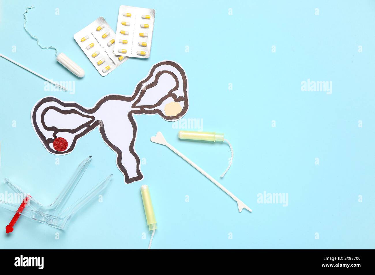 Paper uterus with gynecological speculum, pills and tampons on blue ...