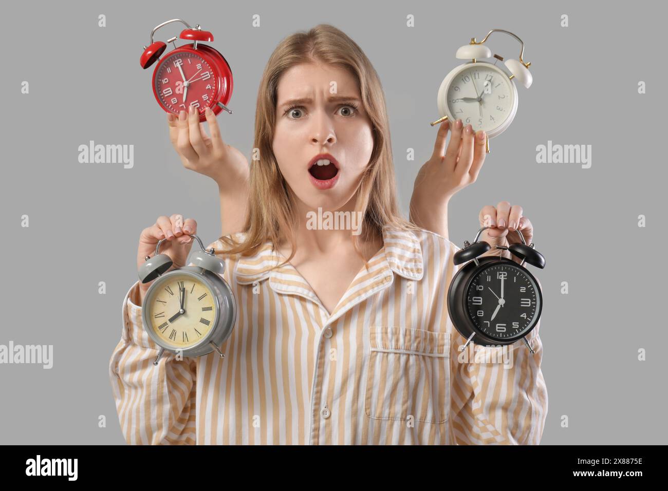 Shocked young woman with many alarm clocks on grey background Stock ...