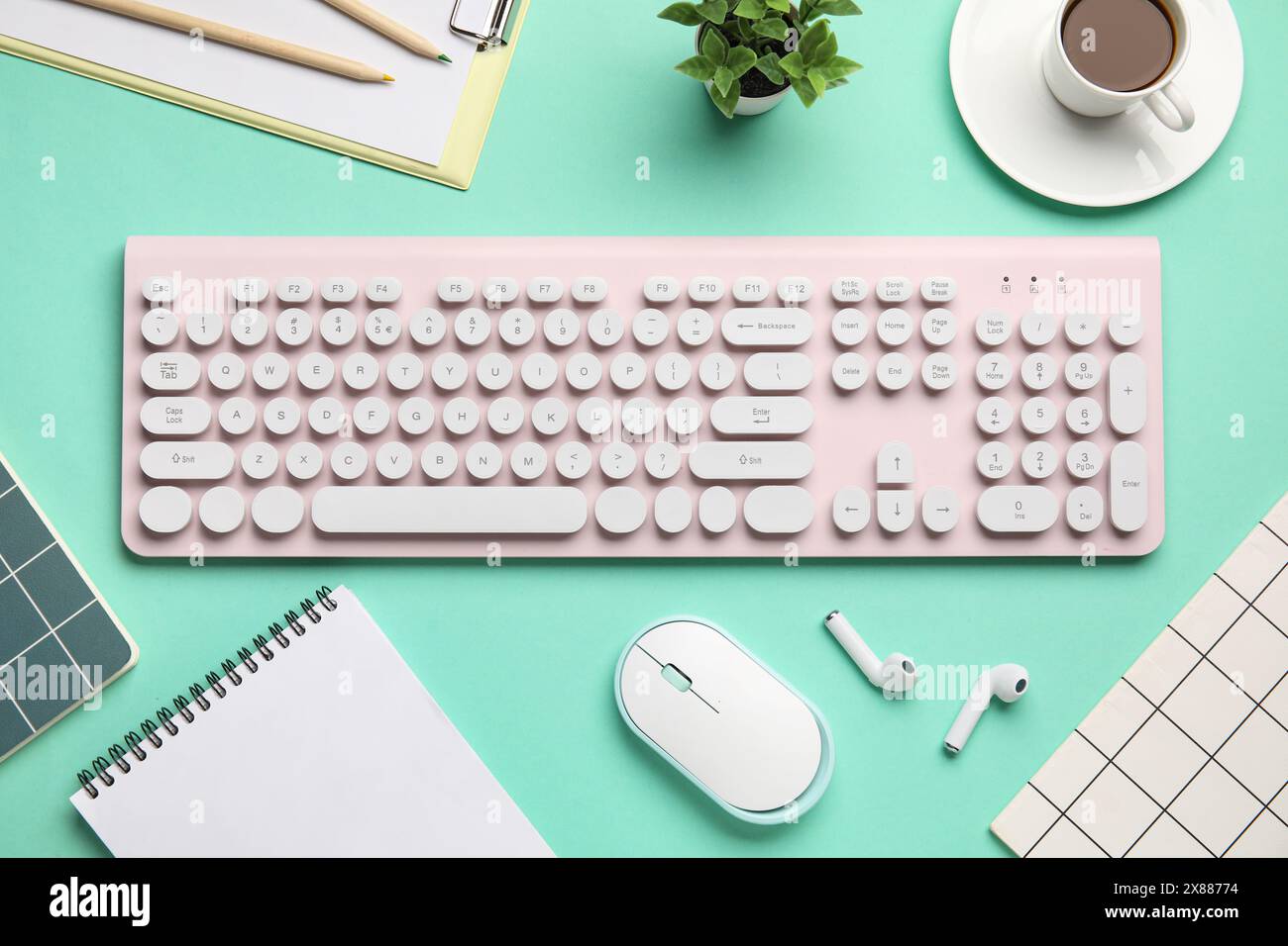 PC keyboard, mouse, earphones, coffee and stationery on turquoise ...