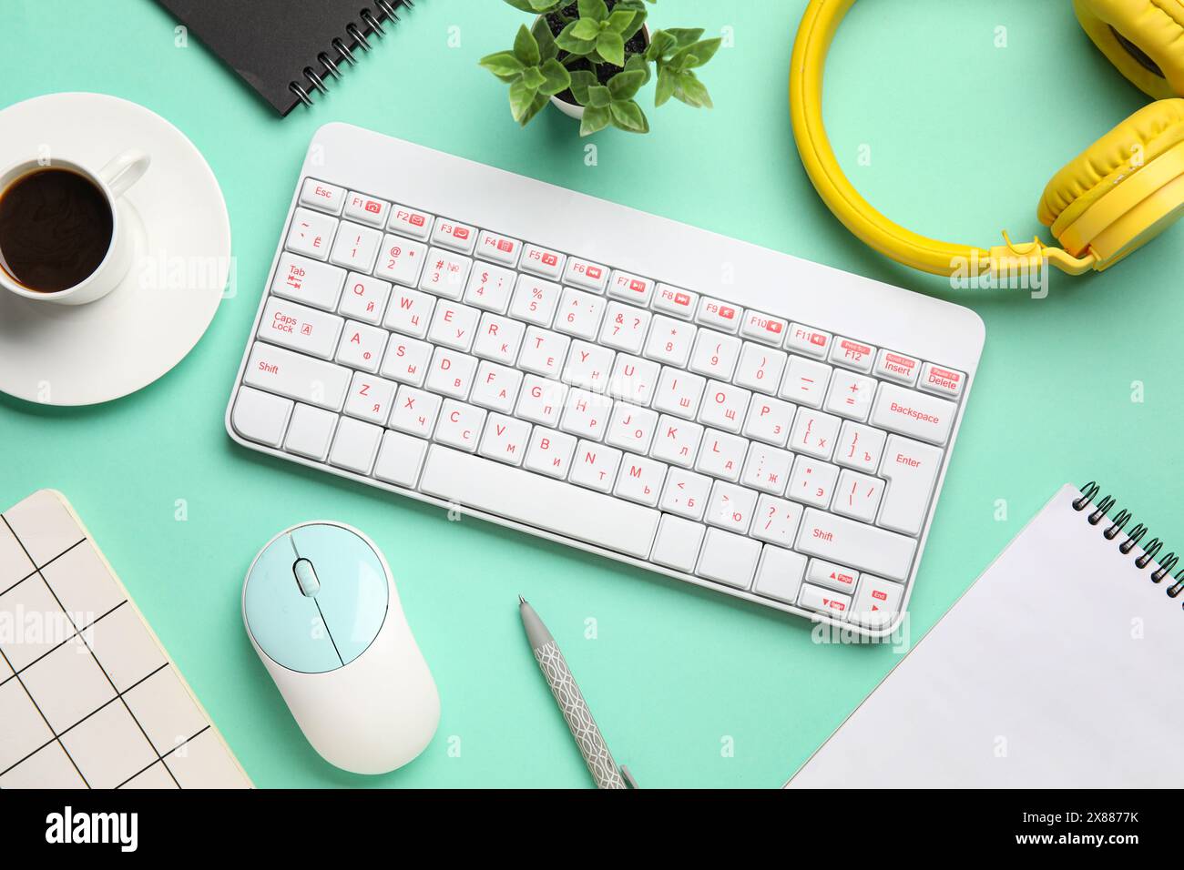 PC keyboard, mouse, headphones, coffee and stationery on turquoise ...