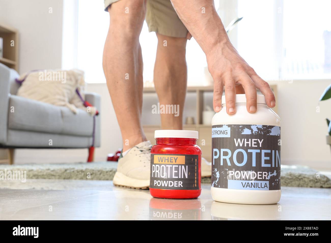 Sporty young man taking protein powder from floor at home, closeup ...