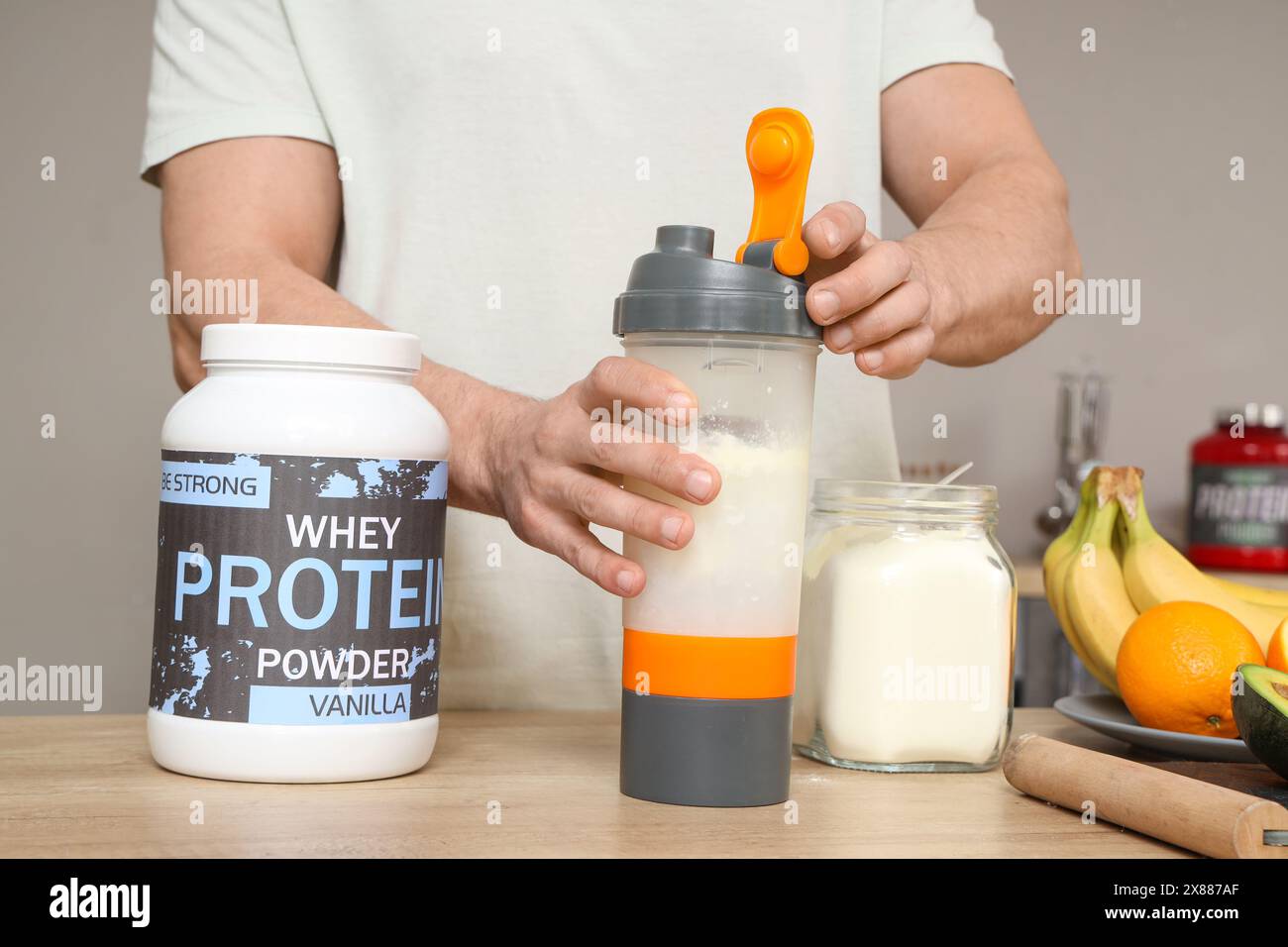 Sporty muscular man making protein shake at table in kitchen, closeup ...