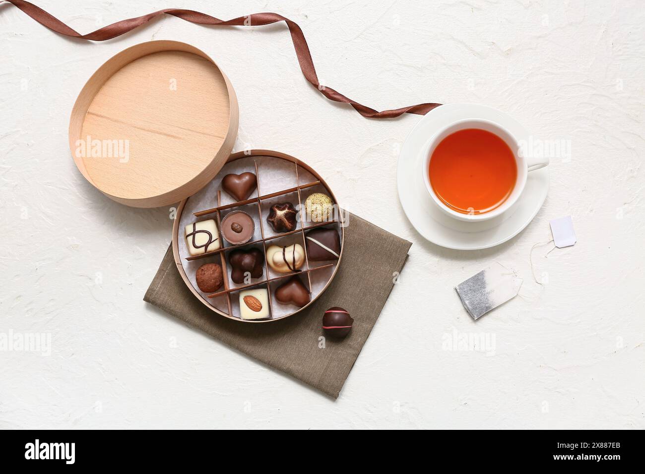 Box with candies, cup of tea and tea bag on light background Stock ...